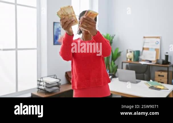 African woman examining south african rand banknotes in a modern office ...