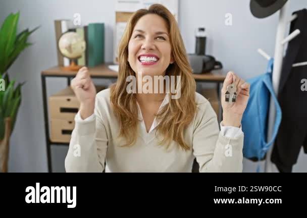 Excited young latin woman celebrates victory in office, proudly holding ...