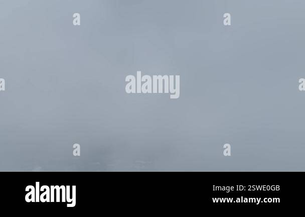 Clouds move across mountain peaks as the forest below lies in shadow ...