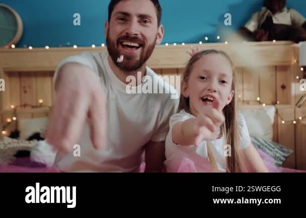 Funny daughter and dad eating throwing pop corn into camera. Portrait ...