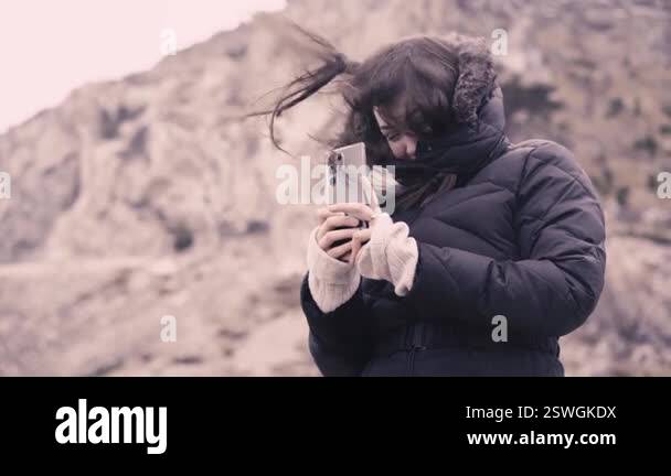 A fearless woman hikes through the rugged mountains on a stormy, wind ...