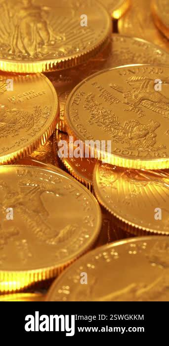 Vertical video of gold coins falling onto a stack of gold eagle US one ...