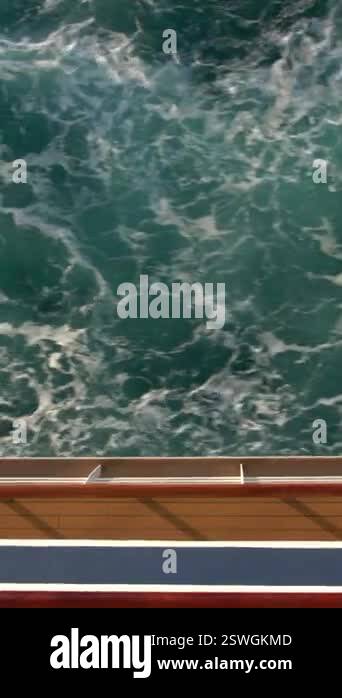 View down the side of a modern cruise ship at the waves created by the ...