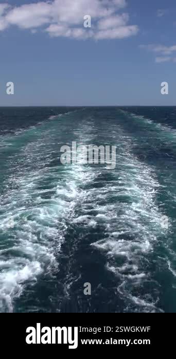 Rear view of ships wake behind cruise ship sailing through calm waves ...