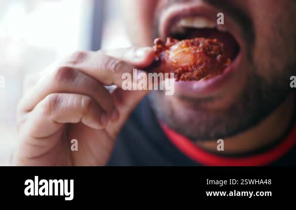 A person savors a delicious spicy chicken wing at a casual restaurant ...