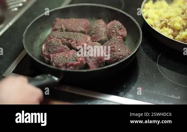 Slow motion video of Big fat juicy steaks in a pan, seasoned, ready to ...