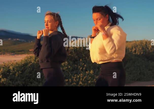 Focused female boxer practicing stance on hill at windy beach during ...
