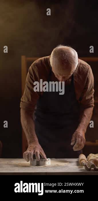 Elderly man using a heart-shaped cookie cutter to cut pieces from ...
