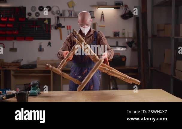 carpenter sanding a chair with a wood sander. production and ...