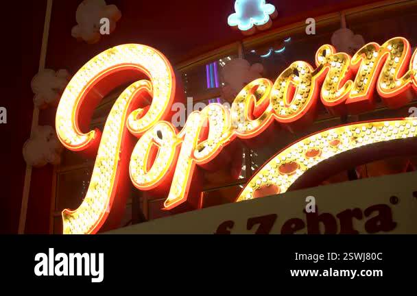 A vibrant neon "Popcorn" sign flashing with bright lights at night, filmed in Los Angeles ...