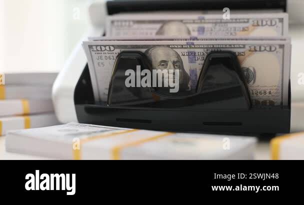 Currency counting machine processes stack of hundred dollar bills ...