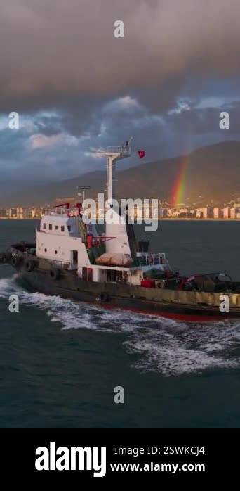 A serene tugboat journey unfolds under a colorful sunset and rainbow ...