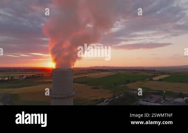 setting sun behind of smoke and steam out of soviet concrete factory ...
