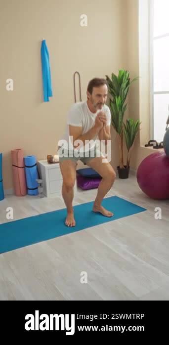Man exercising on yoga mat in indoor wellness room featuring plants ...