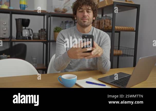 Young man in office taking selfie with smartphone while sitting at desk ...