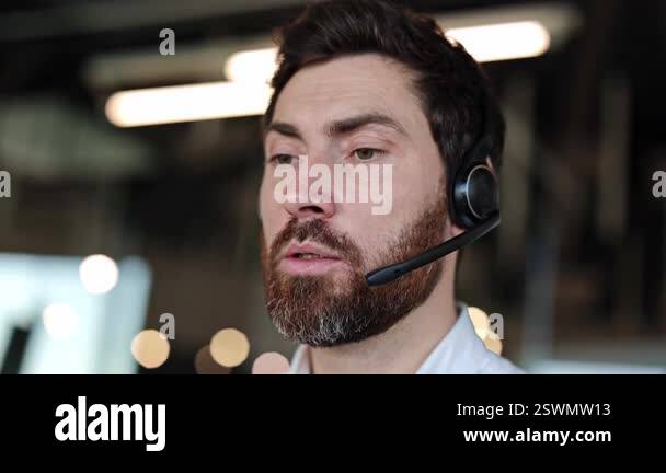 Close up of a focused businessman with a headset talking to a customer ...