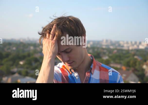 Portrait of young confident man sitting on rooftop at cityscape ...