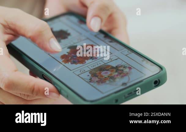 Close up shot of hands of unrecognizable woman browsing items on floral ...