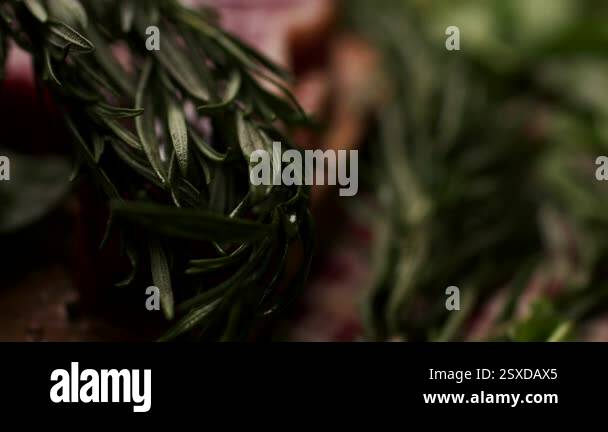 Close-up view of a rosemary twig brushing olive oil on a raw beef steak ...
