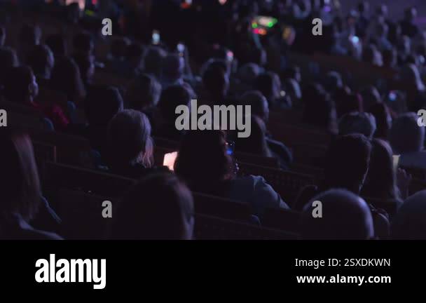 Crowded audience captured from behind while they watch live stage ...