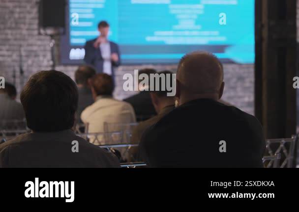 Event featuring attendees listening to a speaker presenting with a ...