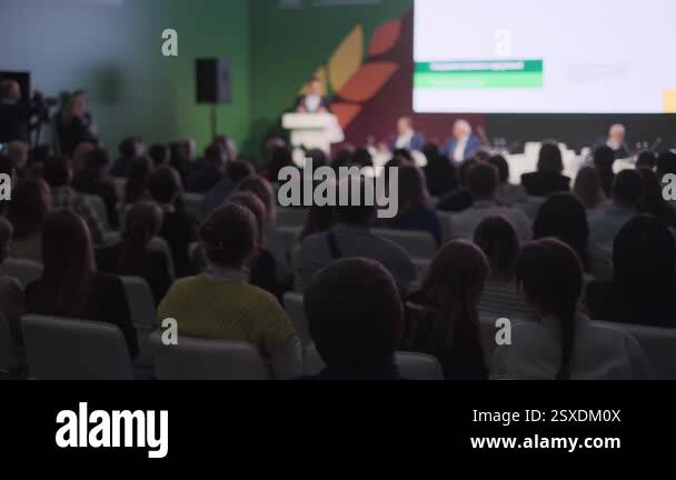 Conference venue with numerous attendees listening to speakers on stage at a business event ...