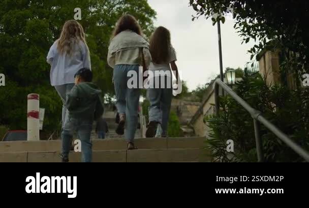 Large family of mother and three children climb stairs while walk in ...