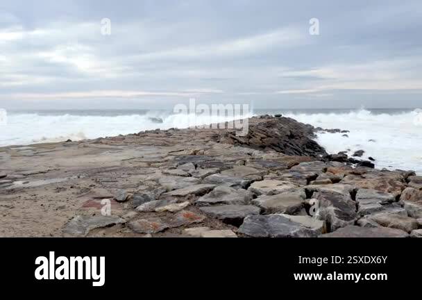 A stone jetty stretches into the turbulent ocean at Furadouro, Portugal ...