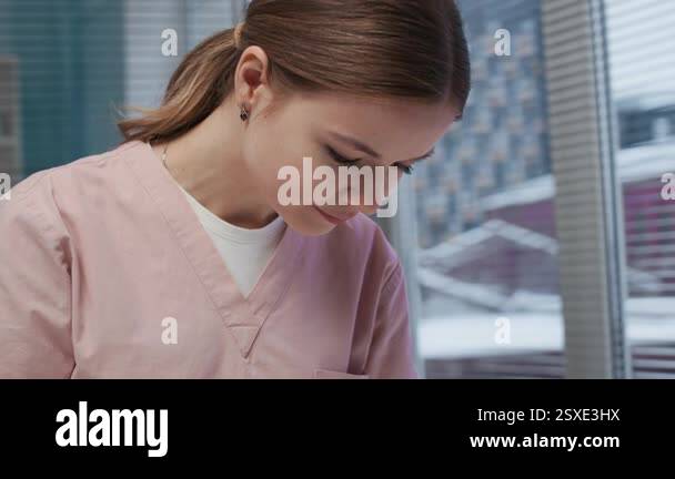 Tilt down shot of young concentrated Caucasian female vet in pink ...