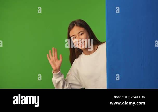 Children emotions concept. Asian girl child peeks out and waves hand ...