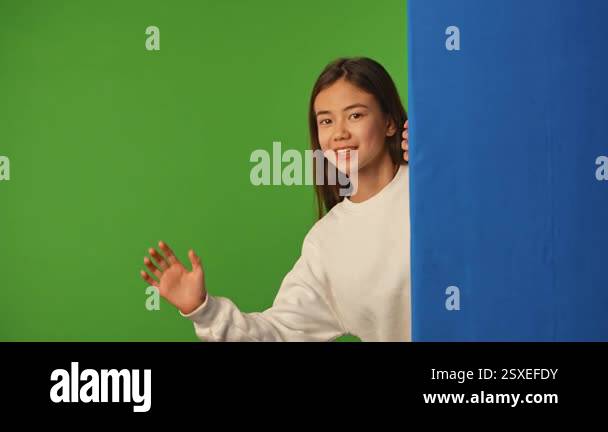 Children emotions concept. Asian girl child peeks out and waves hand ...
