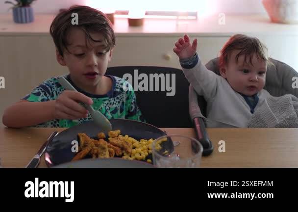 Baby sitting in high chair, raising hand with an expressive gesture ...
