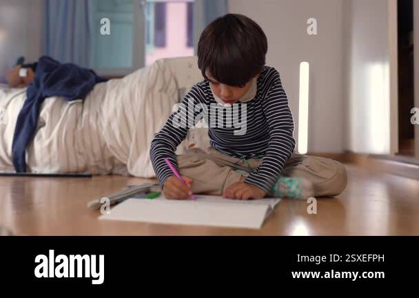 boy carefully adding a block to a colorful structure on the floor ...