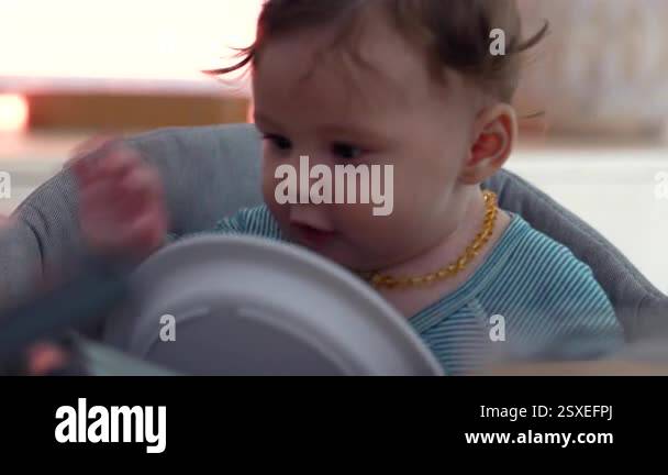Baby biting a white plate, oral exploration, teething behavior, sitting ...