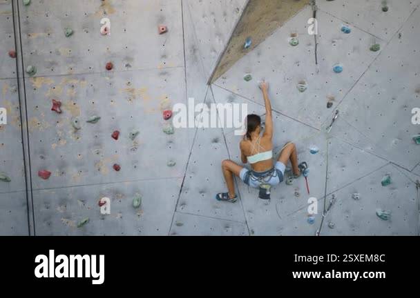 female rock climber practicing on climbing wall, slow motion shot of ...