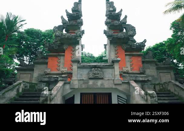 A traditional Balinese temple entrance with intricate stone carvings ...