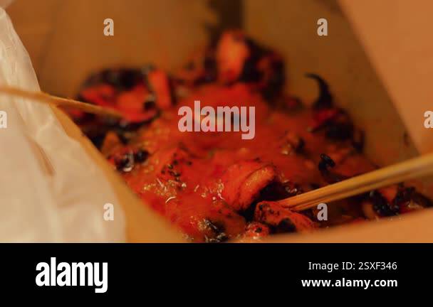 A close-up view of a takeout box containing a spicy seafood dish ...