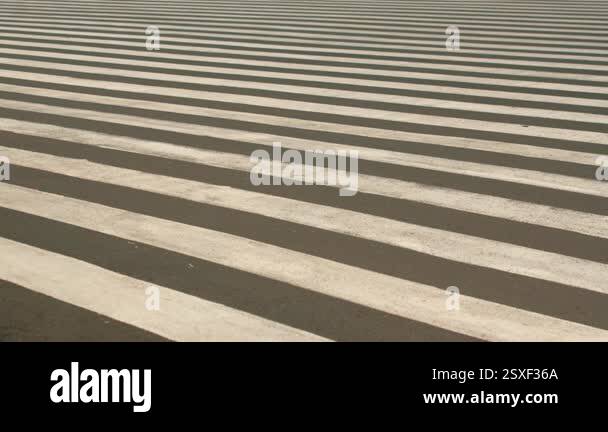 A close-up view of a crosswalk with alternating white and dark stripes ...