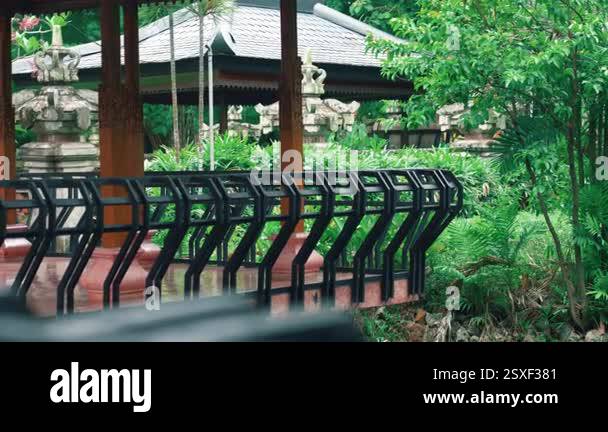 A tranquil garden scene featuring a wooden bridge with a black railing ...