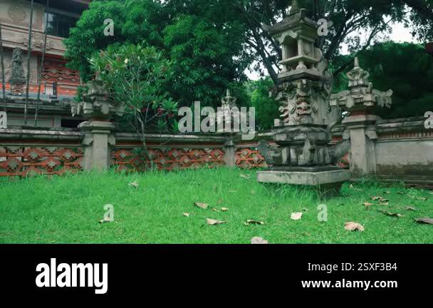 A serene garden scene featuring lush green grass, traditional Balinese ...