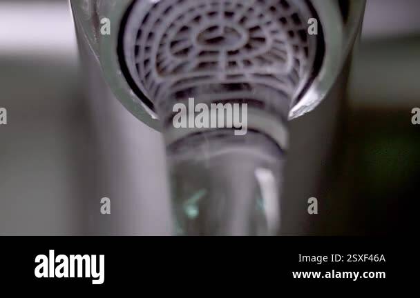 Water flows from sleek chrome-plated faucet, shifting focus from ...