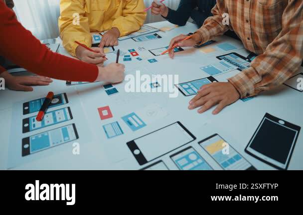 A diverse team engaged in collaborative wireframe design for a mobile ...