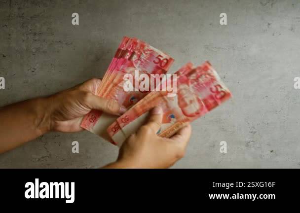Hands counting fifty peso bills against a concrete background in the ...