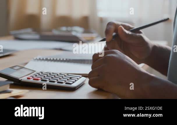 Closeup of hands of unrecognizable black man adding up living costs and ...