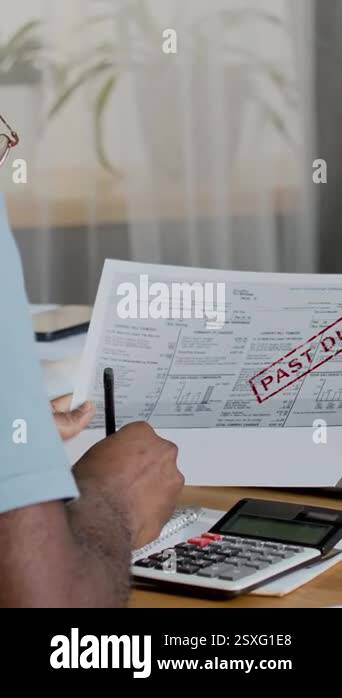 Vertical rear closeup of black male homeowner sitting at desk, holding ...