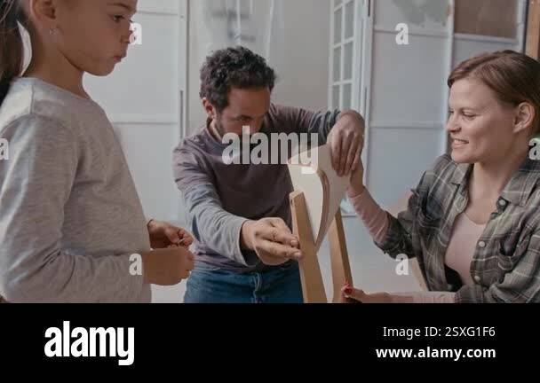 Young family of mother, father and little daughter fixing back part of ...