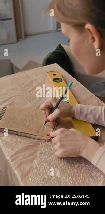 Vertical shot of young woman bending over table covered with protective ...