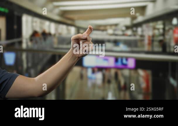 Man's hand gesturing thumbs-up and pointing indoors at a busy mall ...