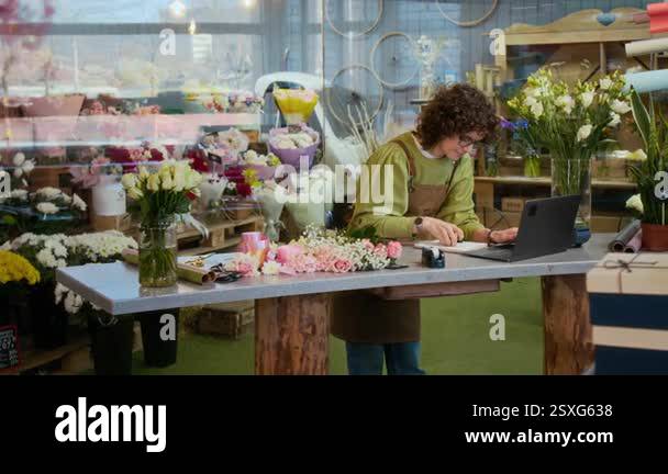 Professional florist writing down details of online order in notebook ...