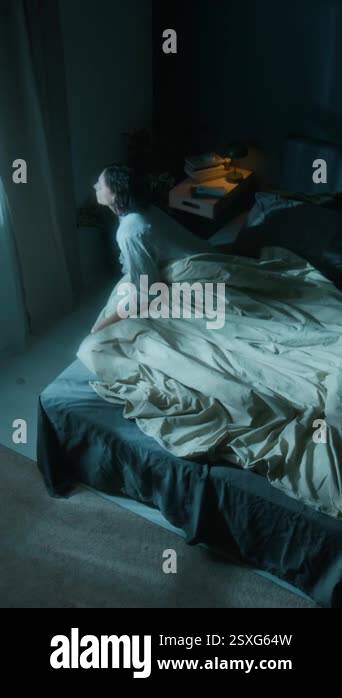 Vertical high angle shot of female sleepwalker waking up in middle of ...